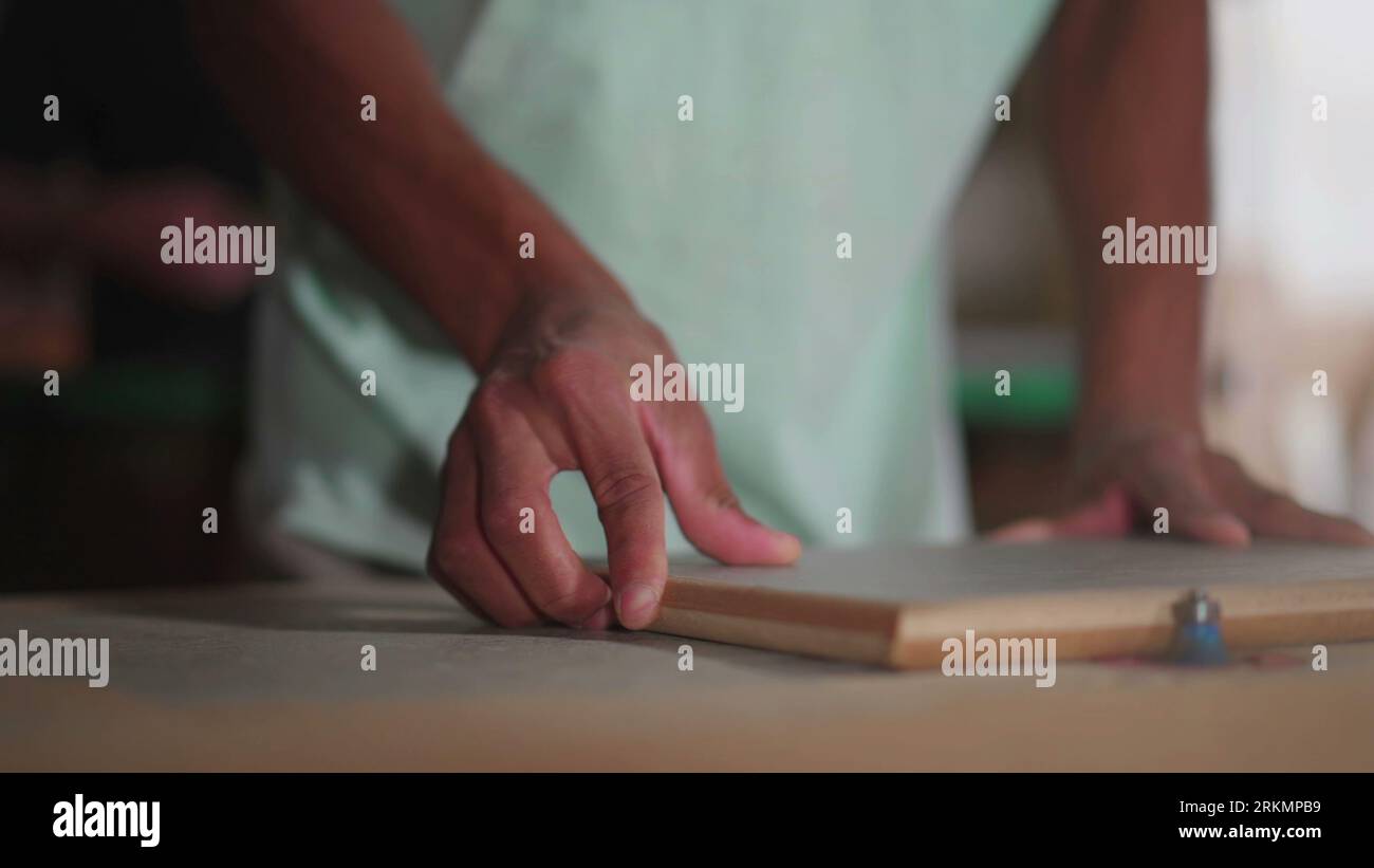 One concentrated young black carpenter engaged with his work, trimming ...