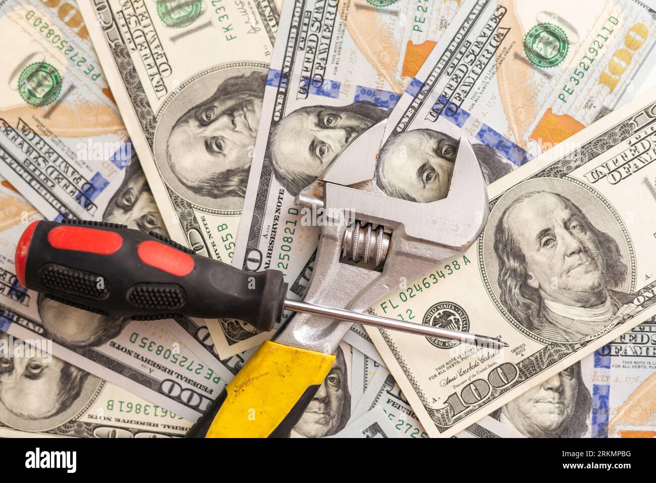Tools lying over 100 dollars banknotes background. Pliers and ...