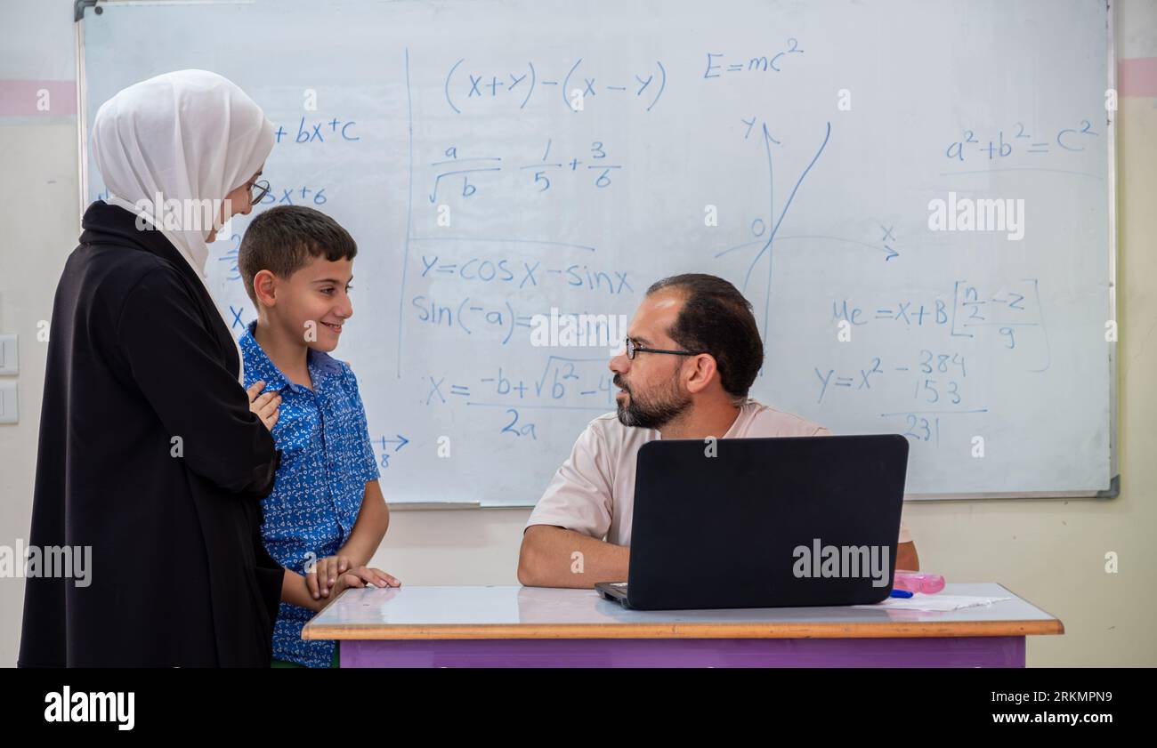 Mother having conversation with the teacher in school about here son academic Progress Stock ...