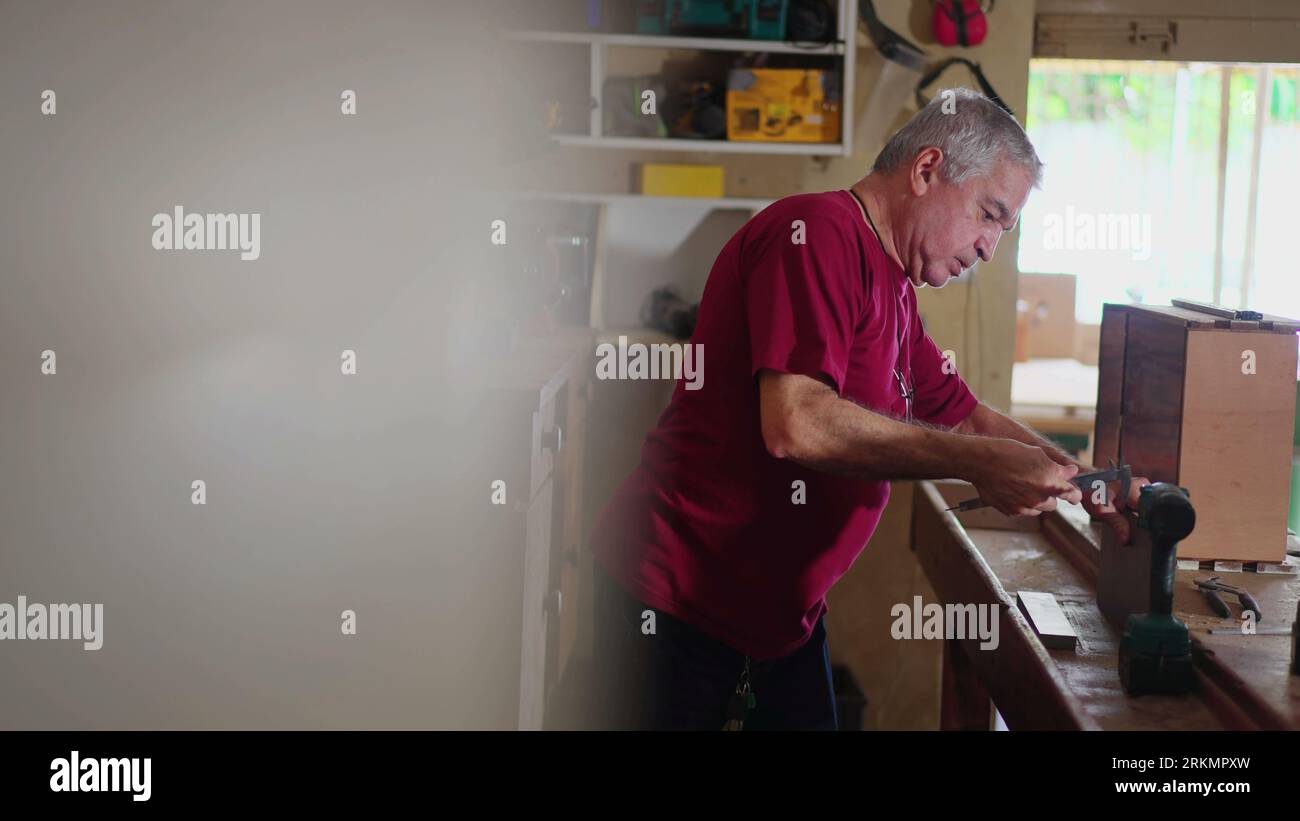 Older man working at workshop, grabbing tools from wall and engaged ...