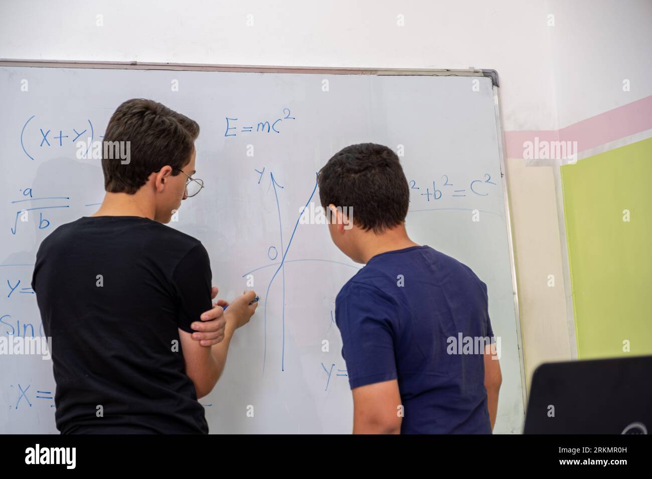 Two students are studying together using the whiteboard in school Stock ...