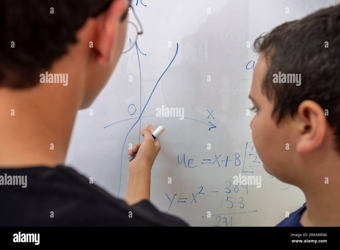 Two students are studying together using the whiteboard in school Stock ...