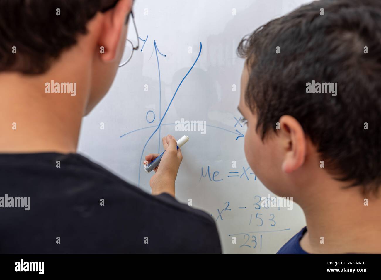 Two students are studying together using the whiteboard in school Stock ...