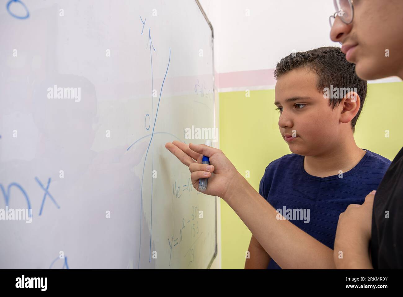 Two students are studying together using the whiteboard in school Stock ...
