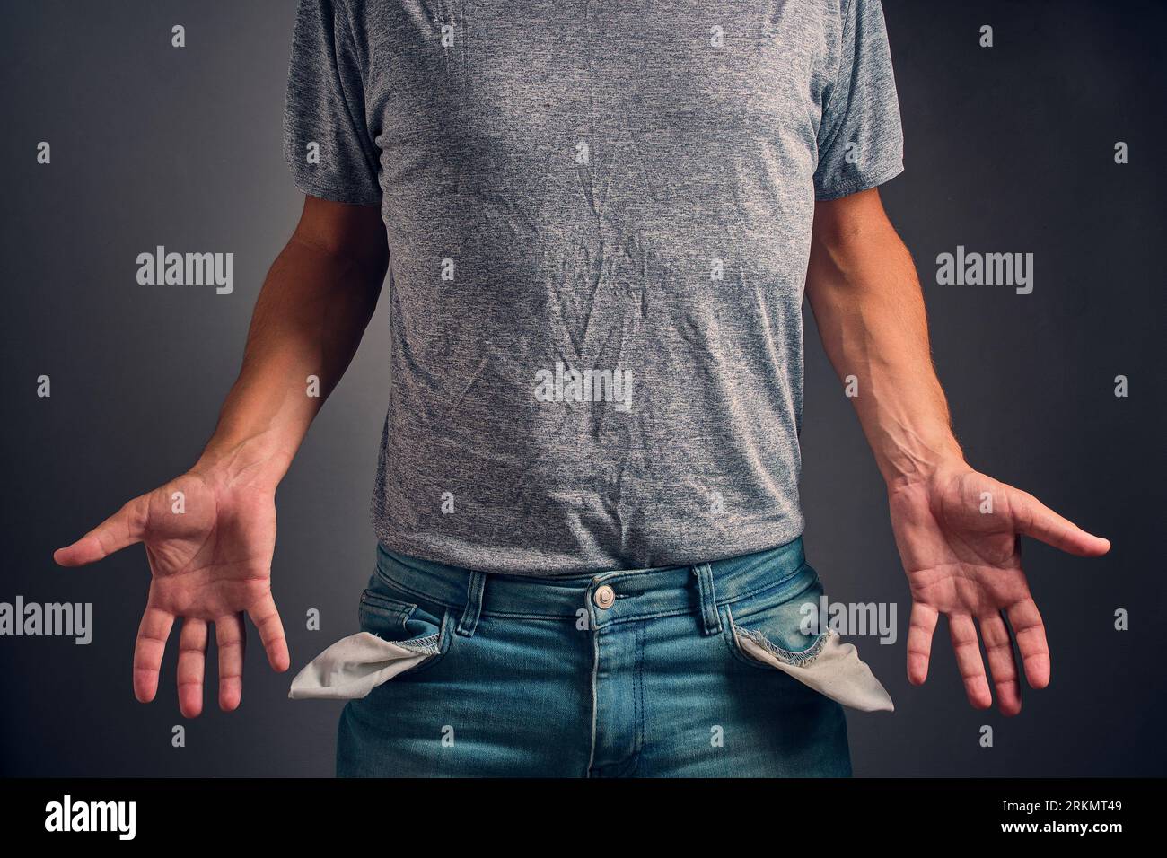 Man in gray crumpled T shirt and jeans with turned out, empty pockets ...