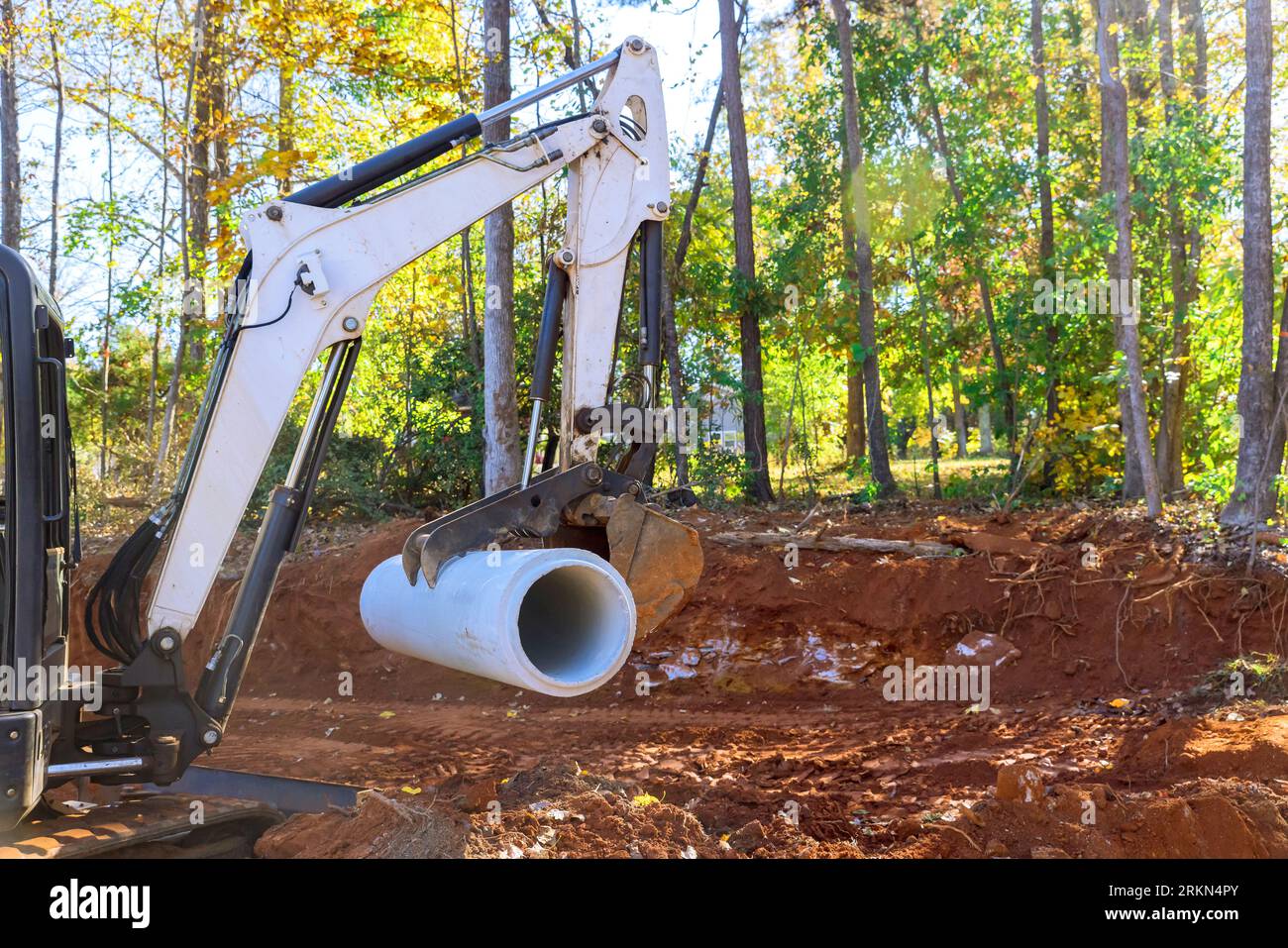 Worker use tractor to lift concrete sewage pipes in ground are being ...