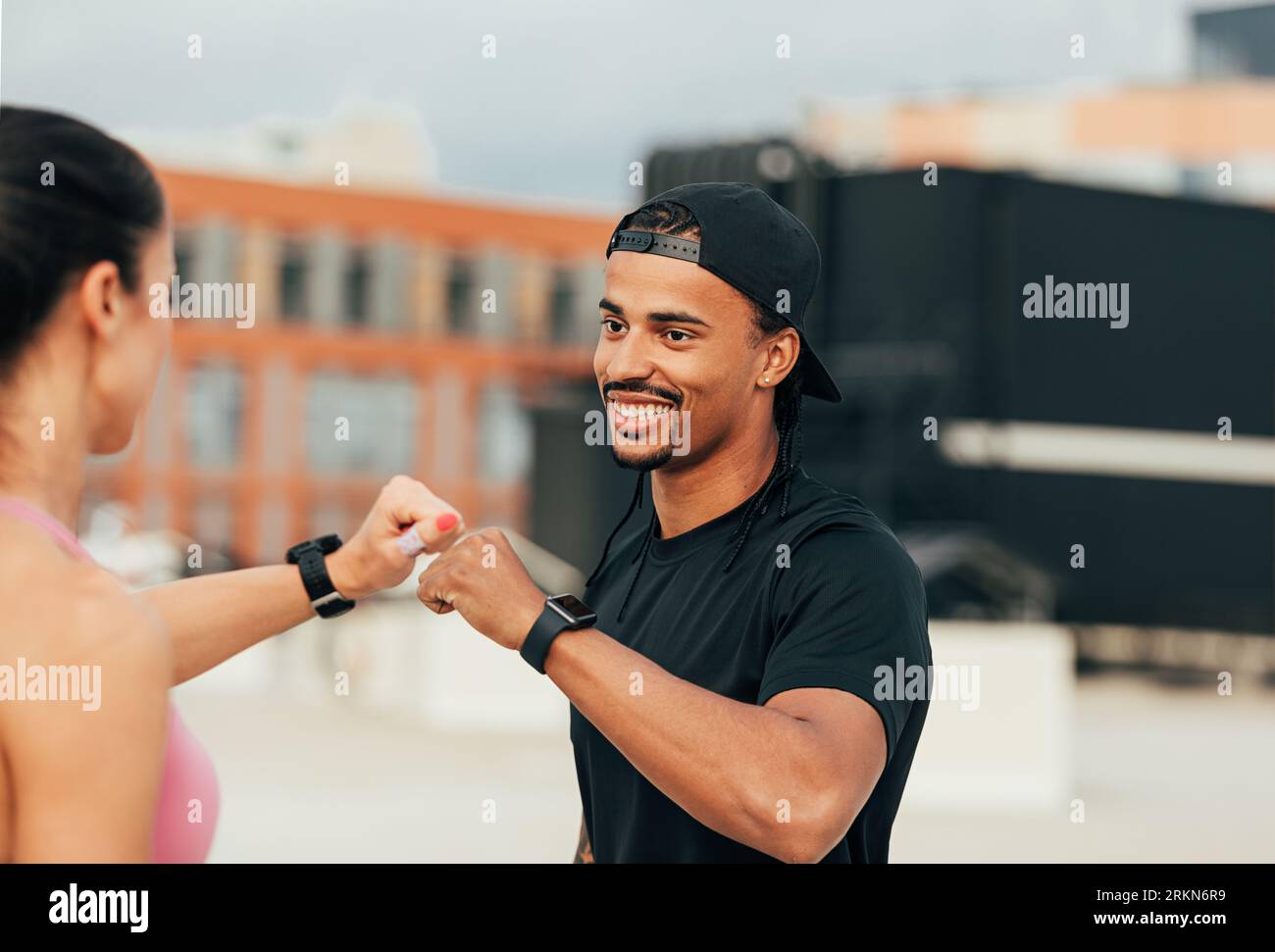 Two fitness people giving fist bumps while standing on the roof Stock Photo - Alamy