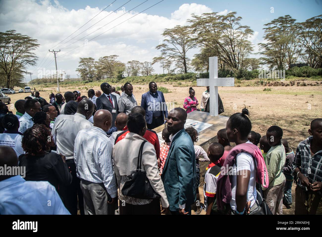 People gather around the commemorative plaque in memory of Rev. Fr ...
