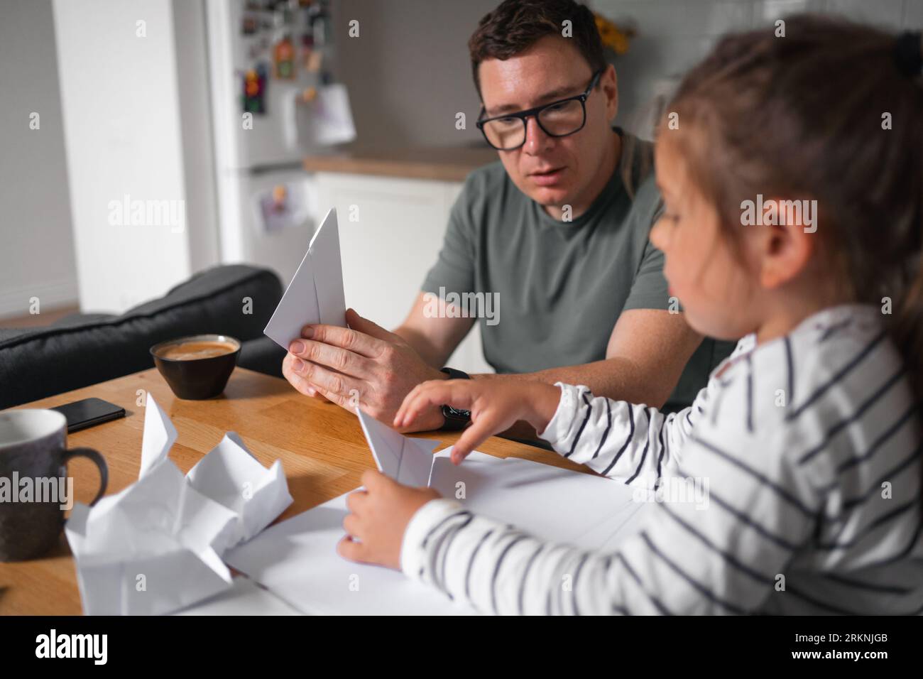Father and child girl doing origami crafts together. Modern parenthood ...