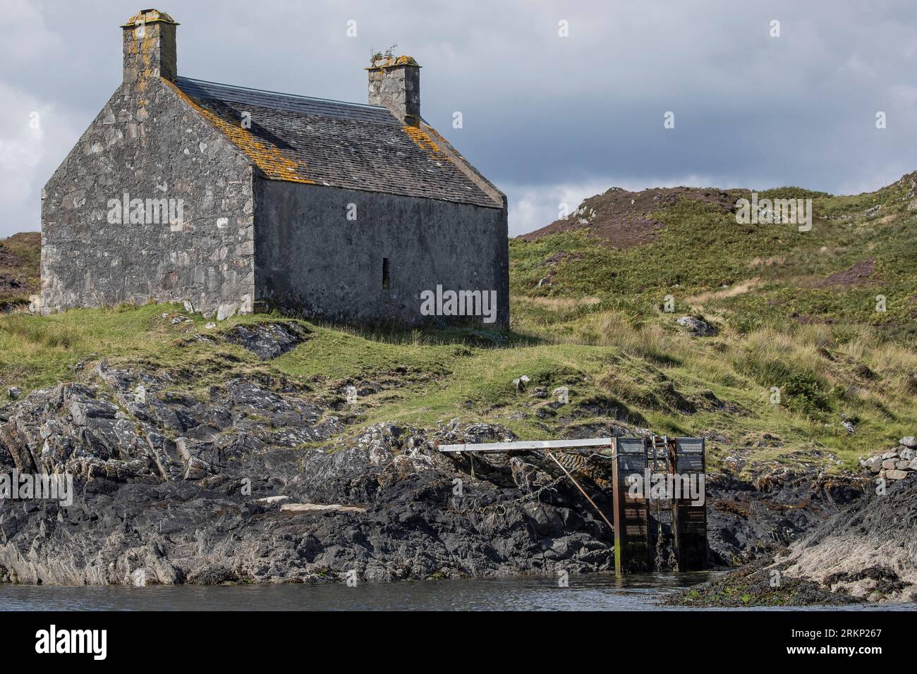 Old greystone building next to a jetty made of metal on a remote island ...
