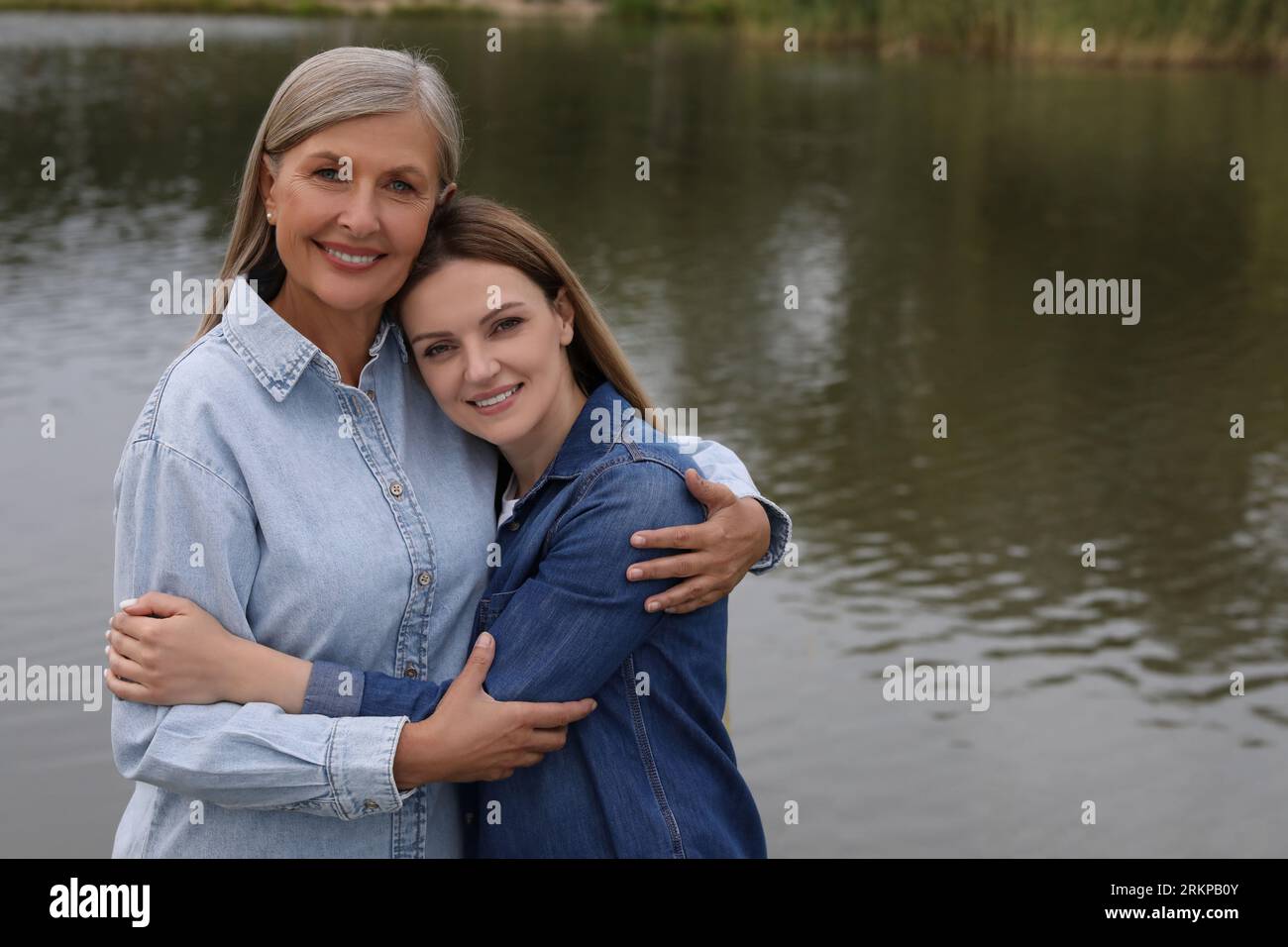 Happy mature mother and her daughter hugging near pond, space for text Stock Photo - Alamy