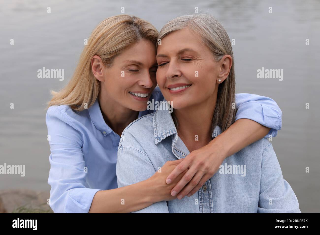 Happy mature mother and her daughter hugging near pond Stock Photo - Alamy