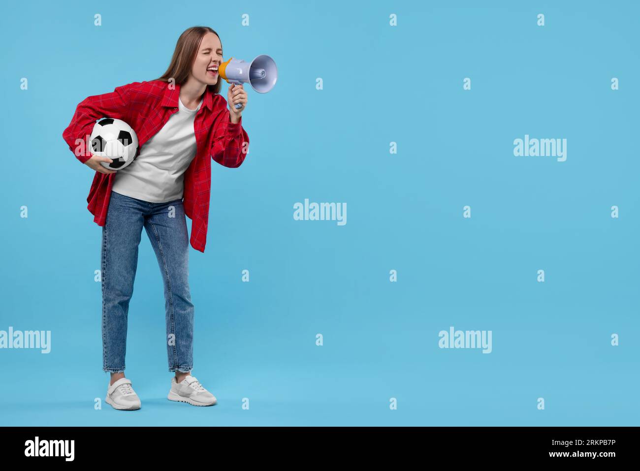 Emotional sports fan with ball and megaphone on light blue background ...