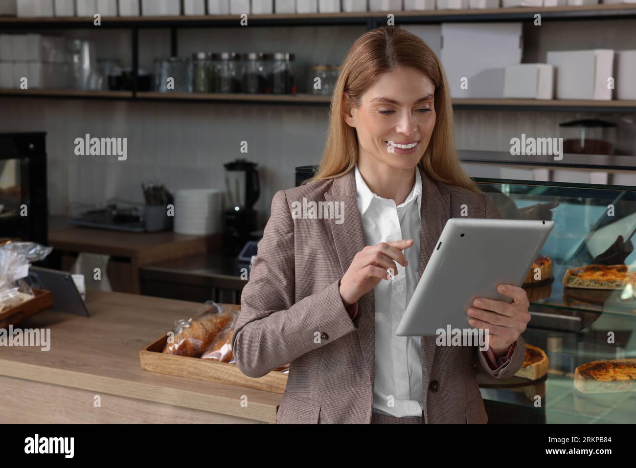 Happy business owner with tablet in bakery shop. Space for text Stock ...