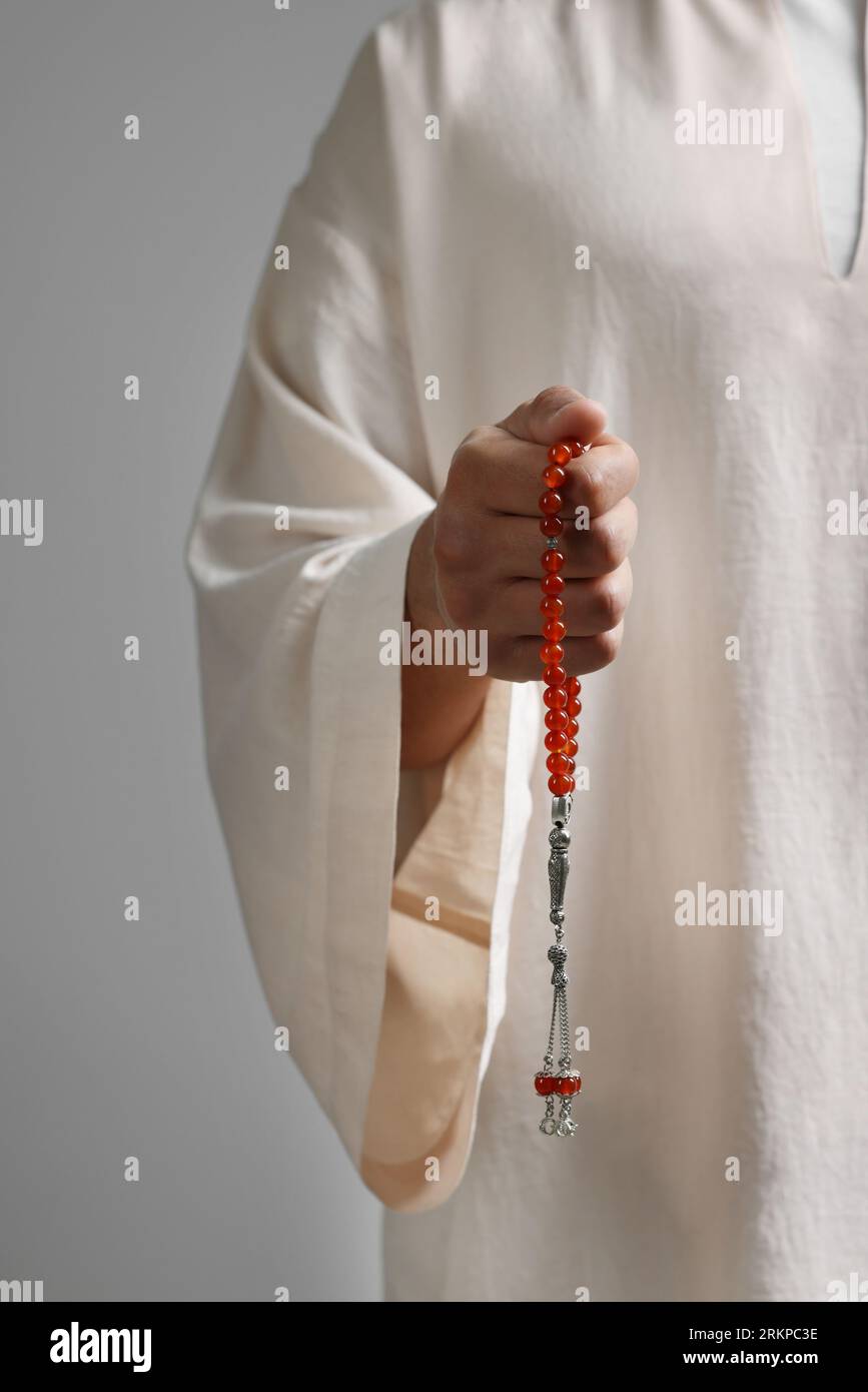 Muslim man with misbaha on light grey background, closeup Stock Photo ...