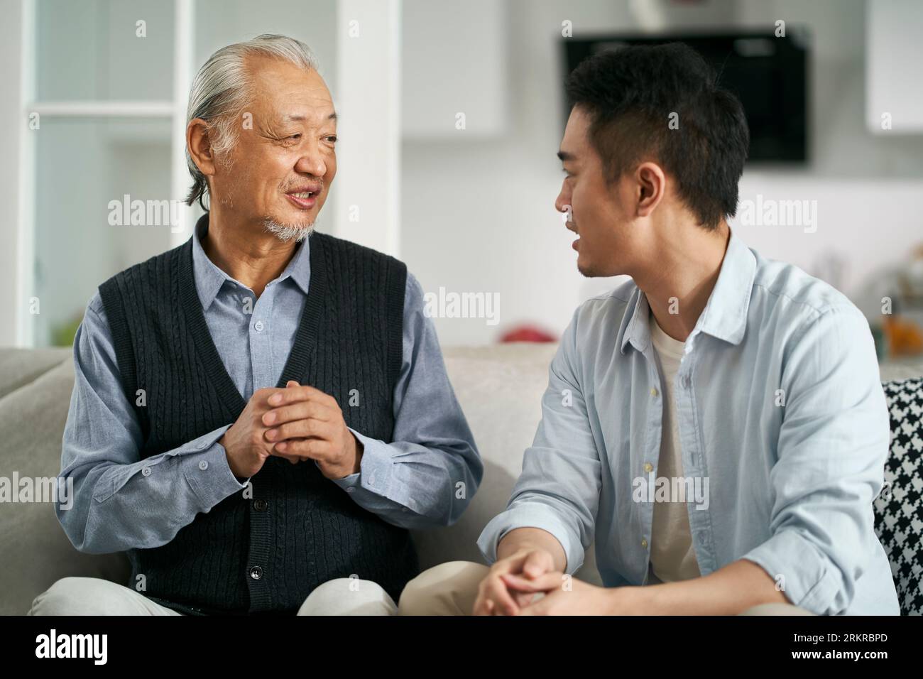 senior asian father having a good time sitting on couch at home ...