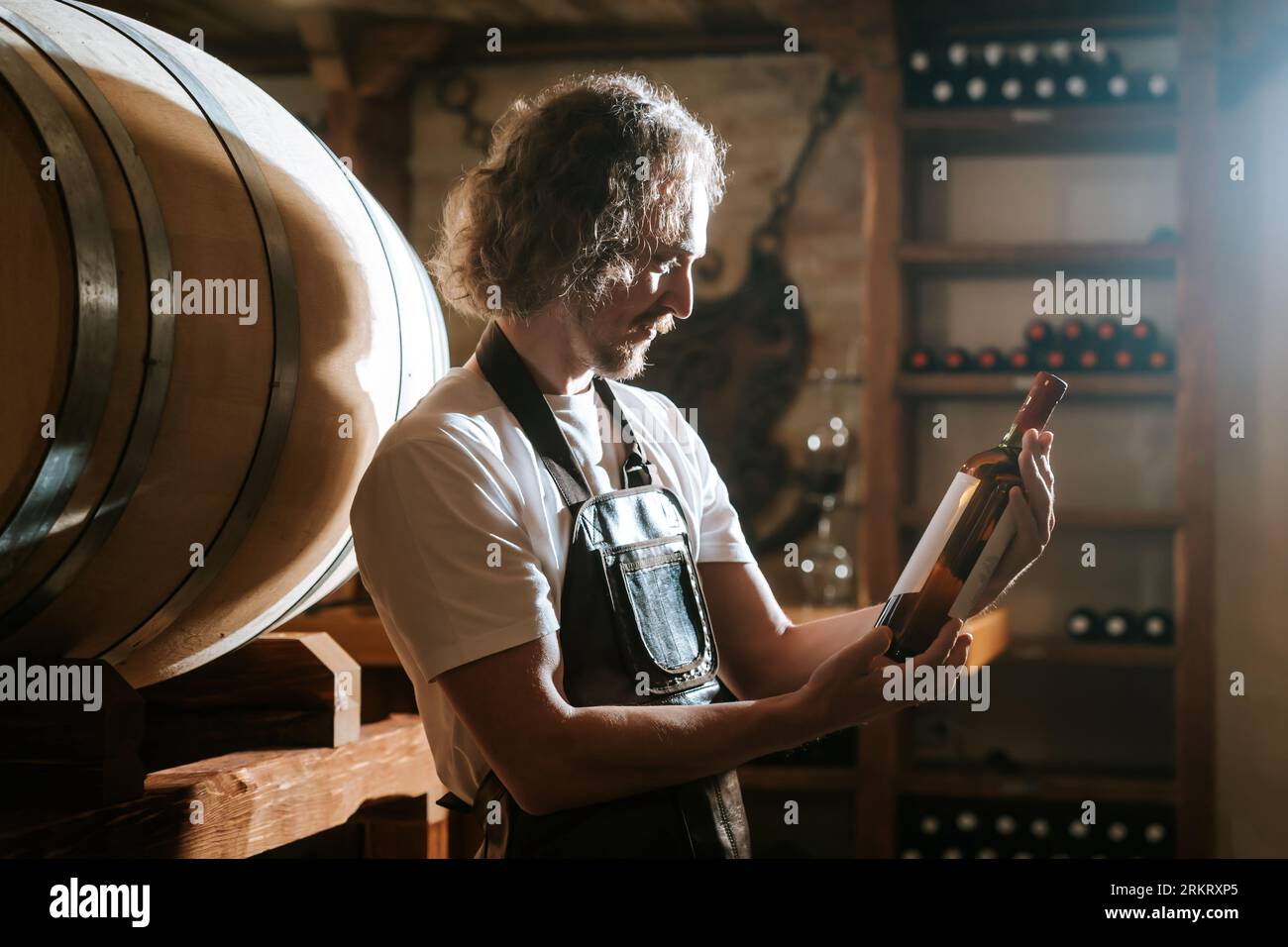 Winemaker tasting wine in a cellar with wooden barrels Stock Photo - Alamy