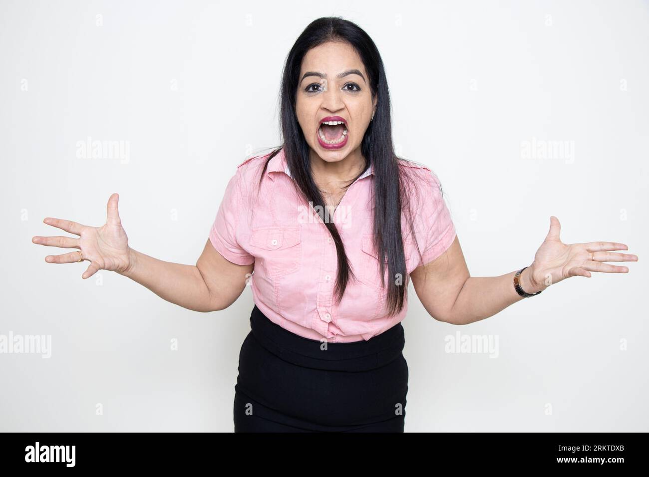 Angry young indian woman wearing formal pink shirt screaming isolated ...