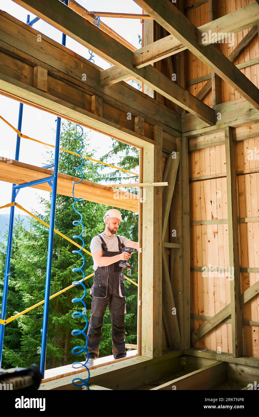 Carpenter constructing wooden framed house. Bearded man worker cladding ...