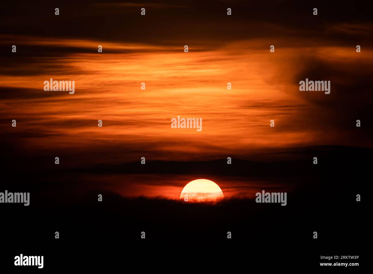 red sky with sun going down half sun behide the sky Stock Photo - Alamy