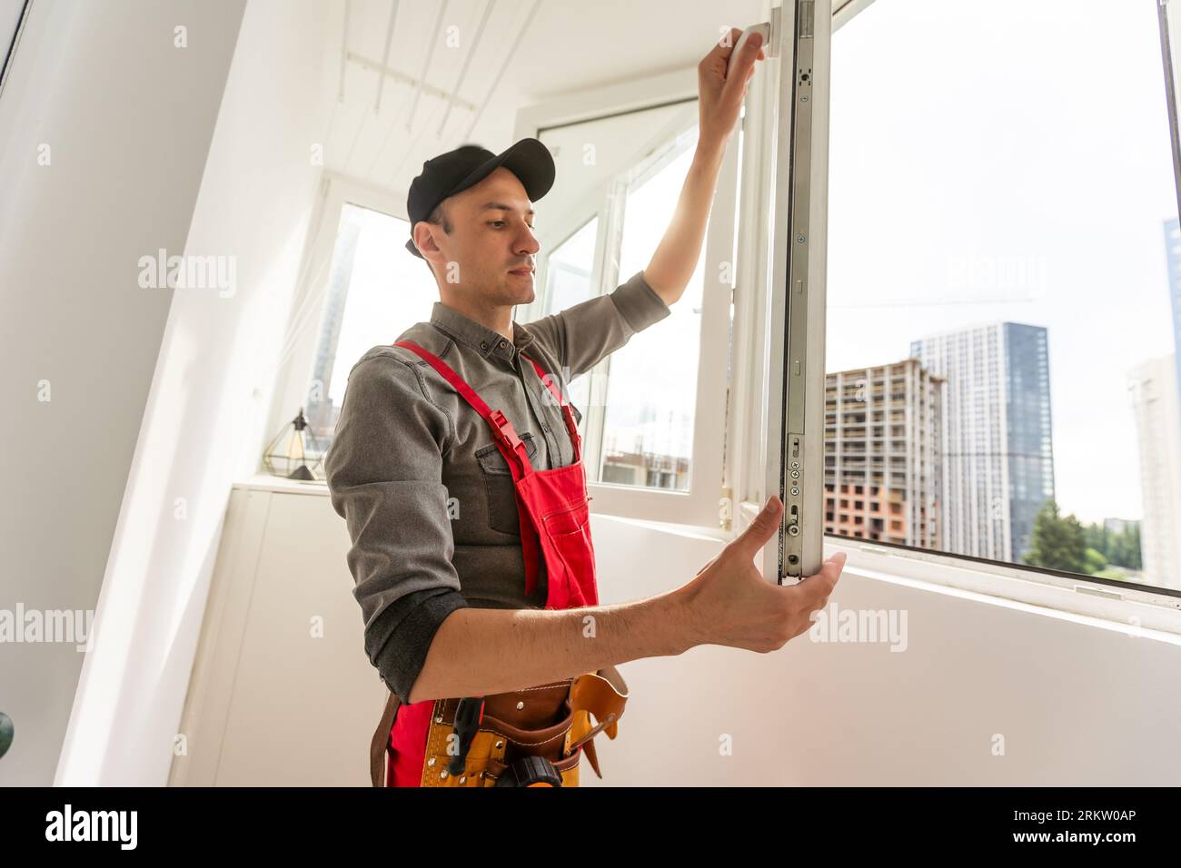 Young repairman fixing window frame in room at daytime Stock Photo - Alamy