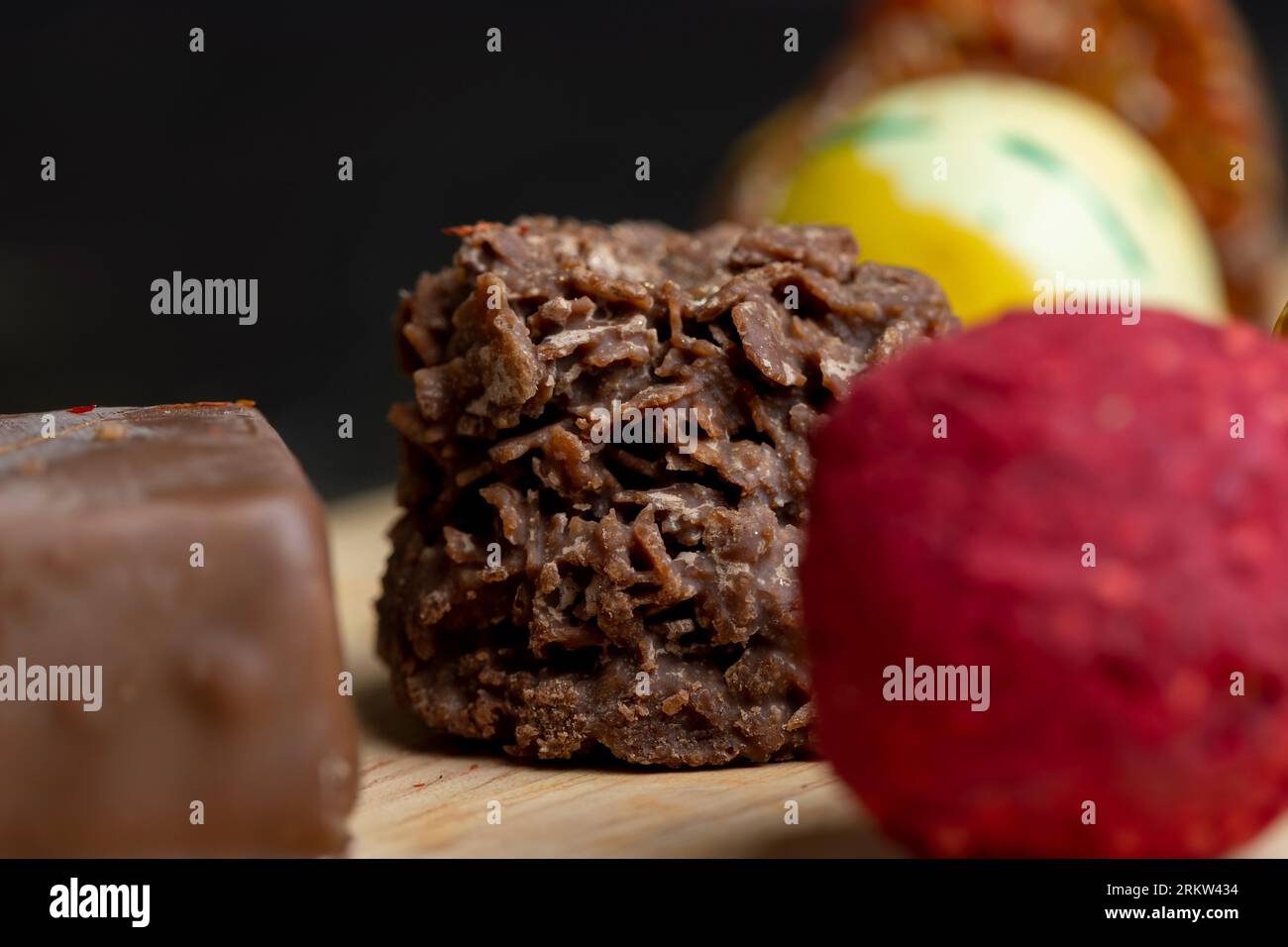 Different chocolates without packaging lying on a wooden board ...