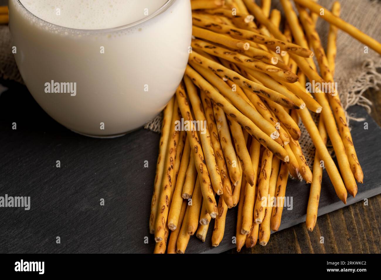 Thin and long bread sticks made of wheat flour and a glass of milk ...