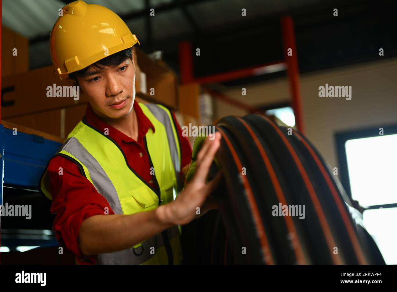 Man worker wearing hard hat carrying plastic tube in warehouse ...