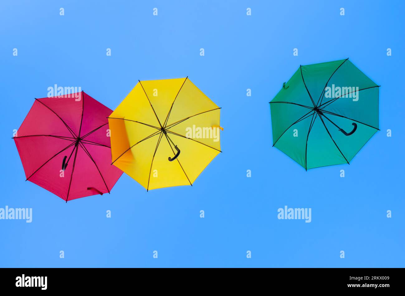 Three colorful umbrellas - red, yellow and green - fly in the blue sky ...
