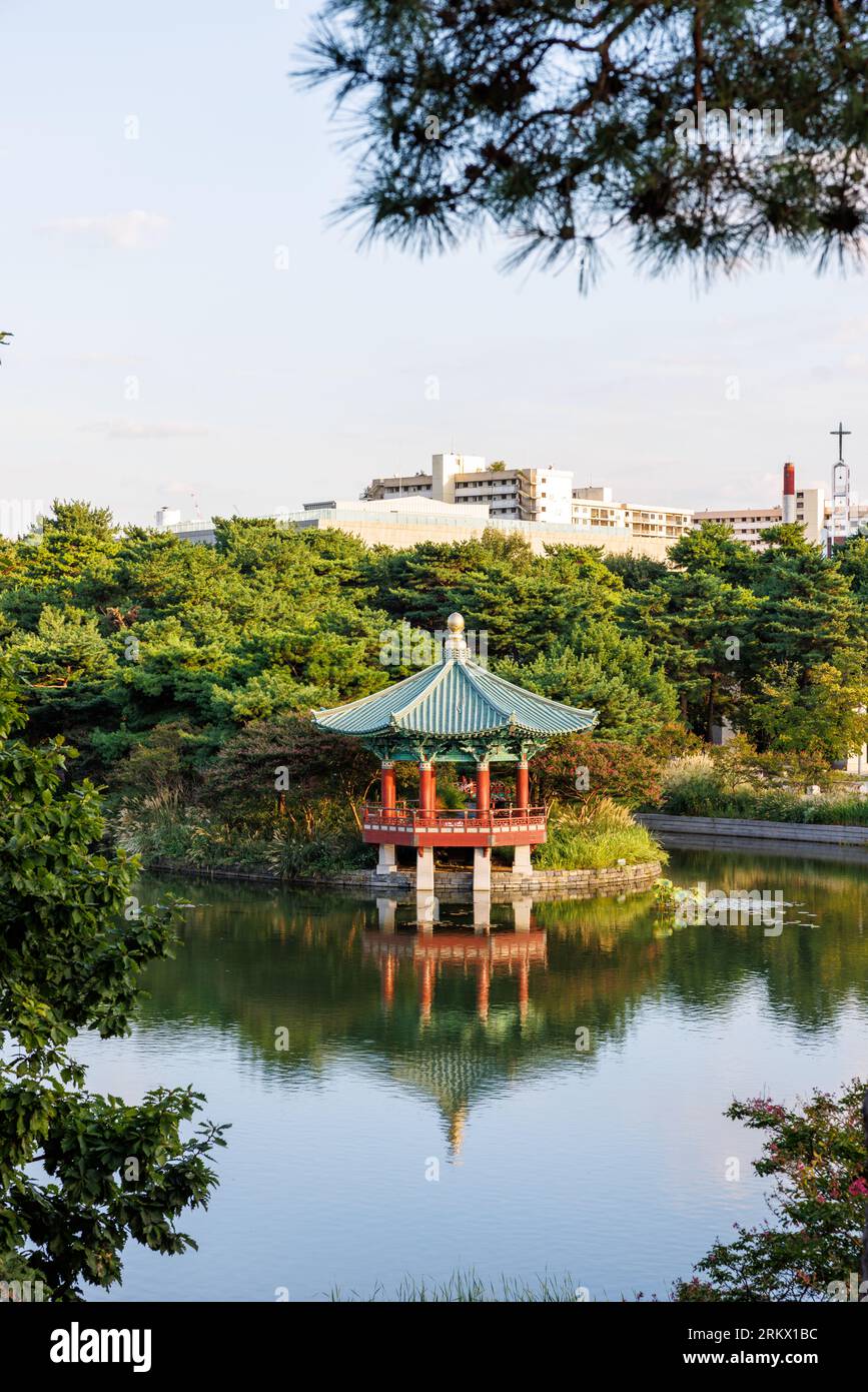 A traditional Korean pavilion in a park by the water near the countries ...