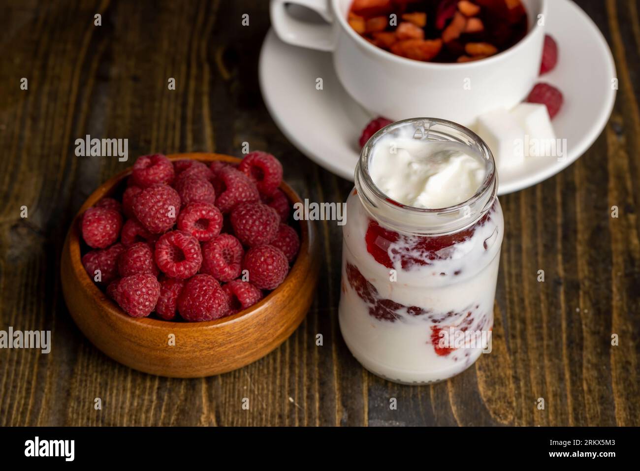 Fresh milk yogurt with whole fresh raspberries, a glass jar with ...