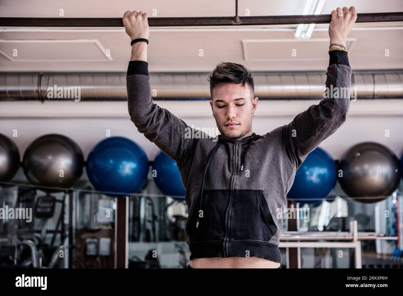 Photo of a young and fit man working out in the gym, lifting his arms ...