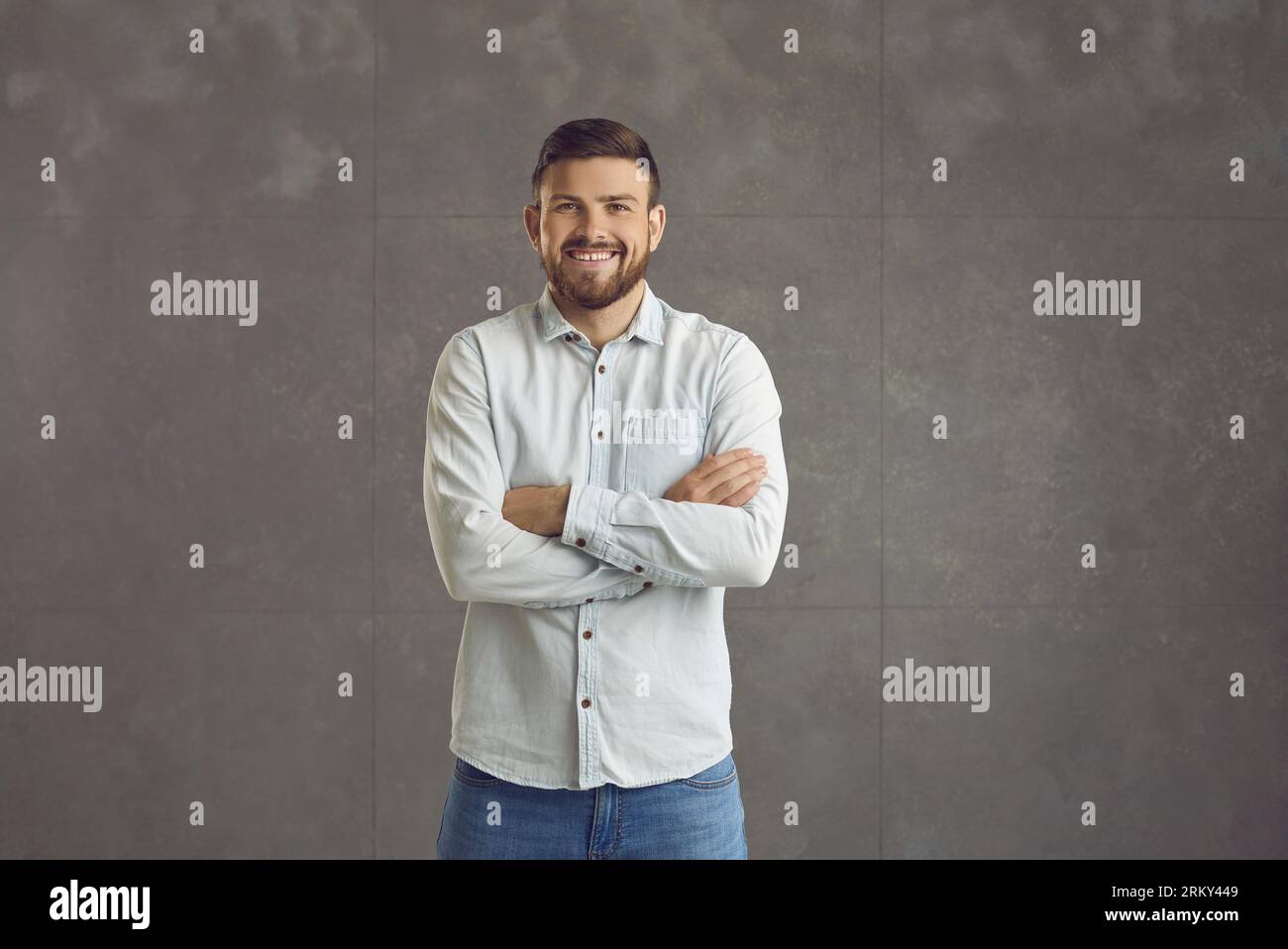 Portrait of smiling handsome young man standing arms crossed against ...