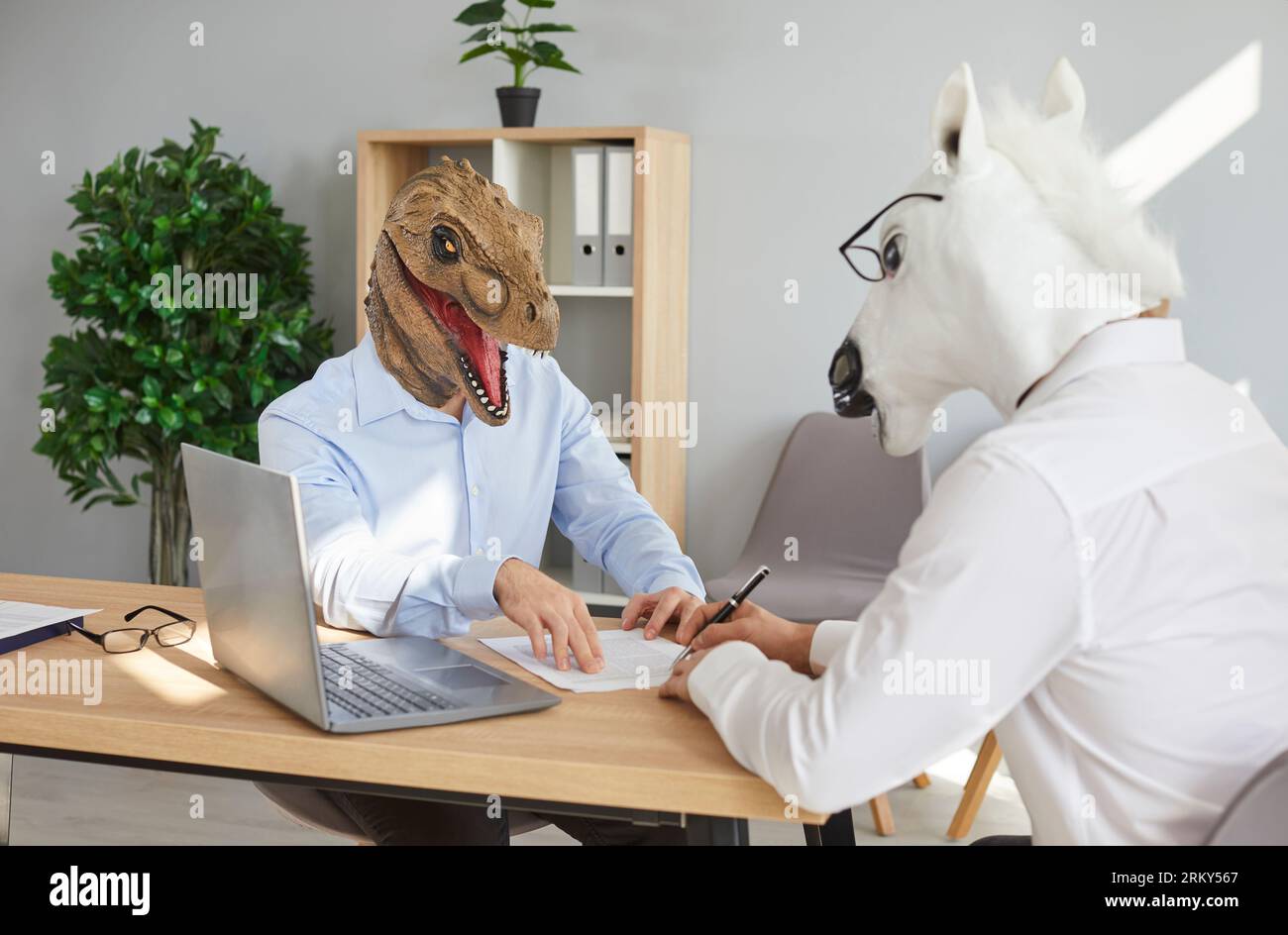 Two businessmen in dinosaur and horse animal masks signing paper ...