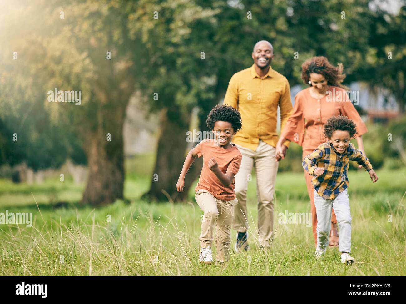 Happy family, running and children at a park with parents, freedom and ...