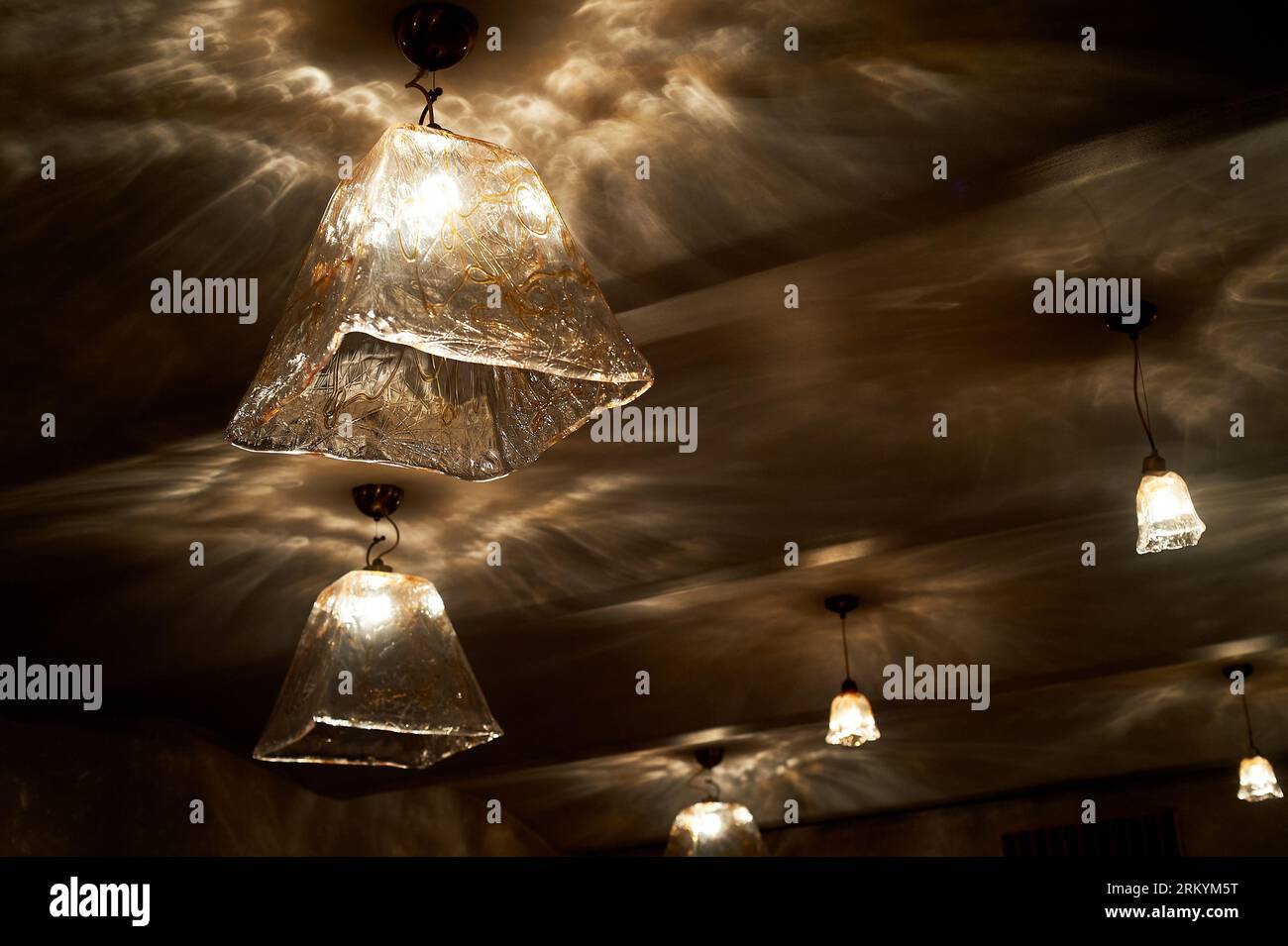 Large glass lamps and glare from them on the ceiling. Warm light Stock ...