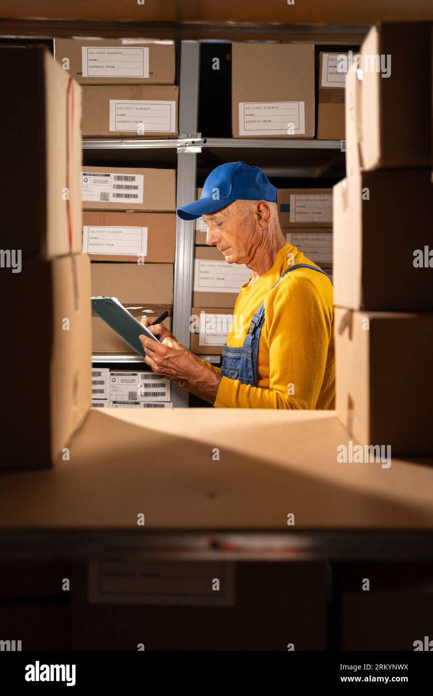 The elderly male inventory manager checks stock using a clipboard. Old ...