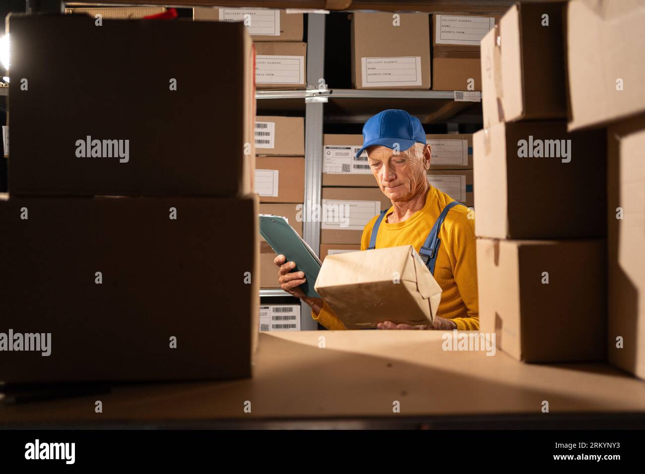 Elderly delivery man or warehouse worker with parcel box and clipboard ...