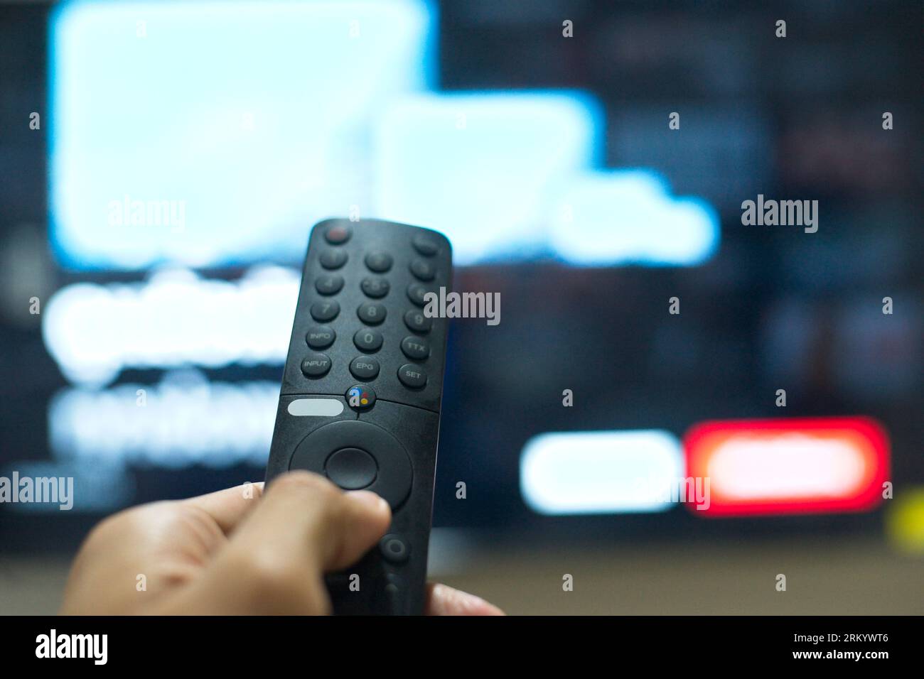 Hand with TV remote control, switching TV series from streaming service ...