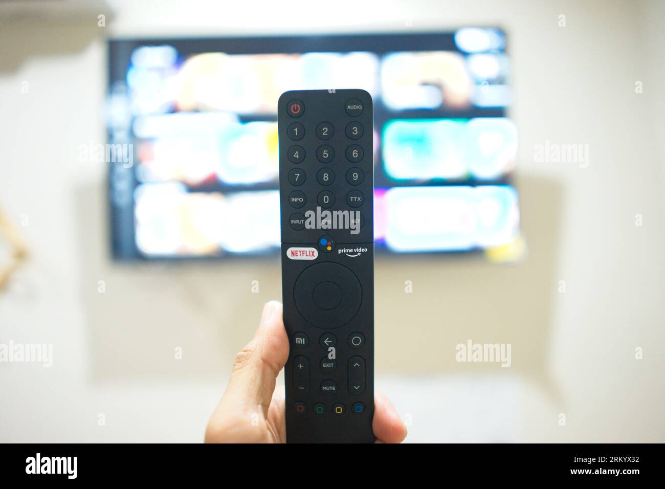 Hand with TV remote control, switching TV series from streaming service ...