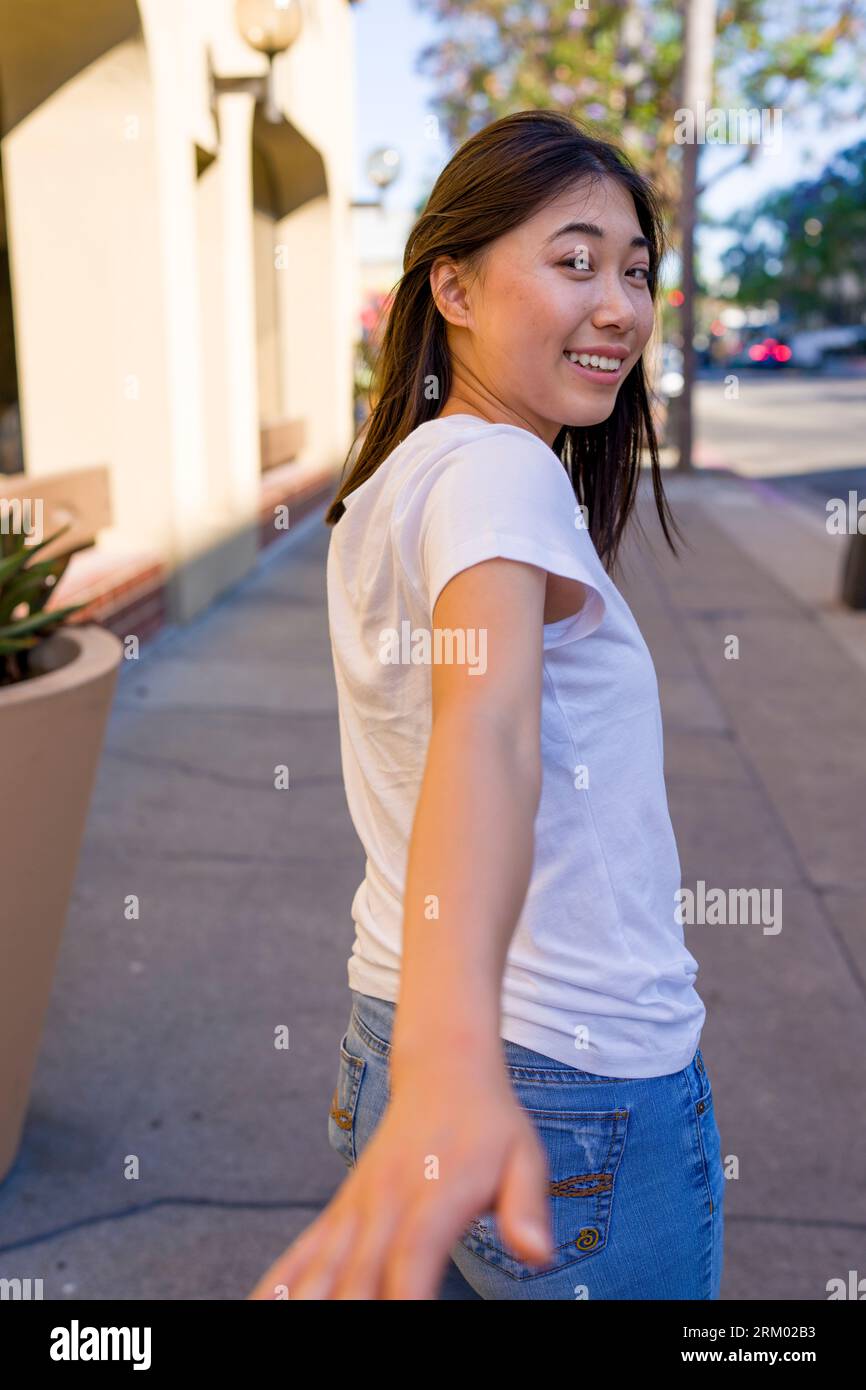 Young Asian Woman Looking Back and Reaching Hand Out to Hold | Downtown ...