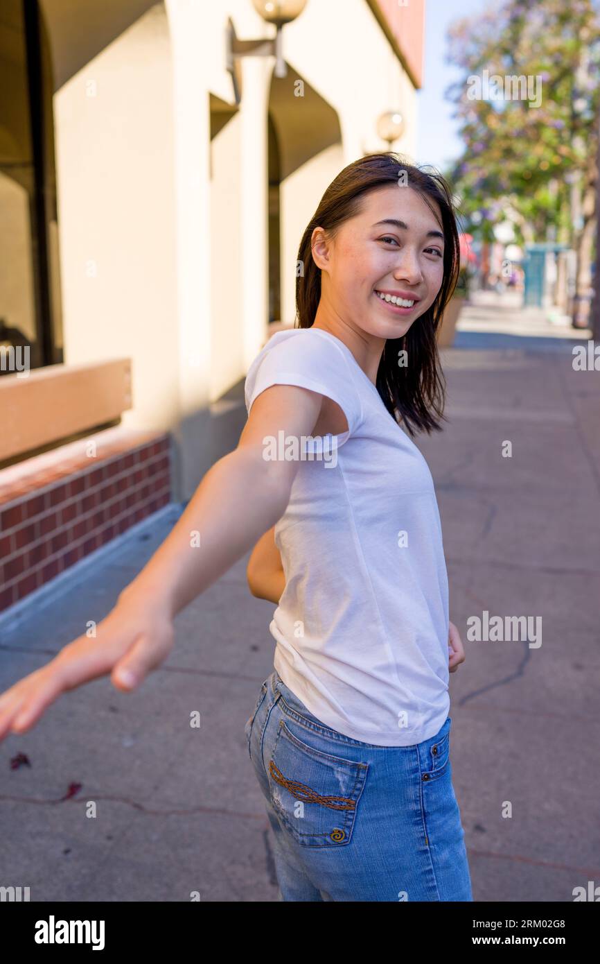 Young Asian Woman Looking Back and Reaching Hand Out to Hold | Downtown ...