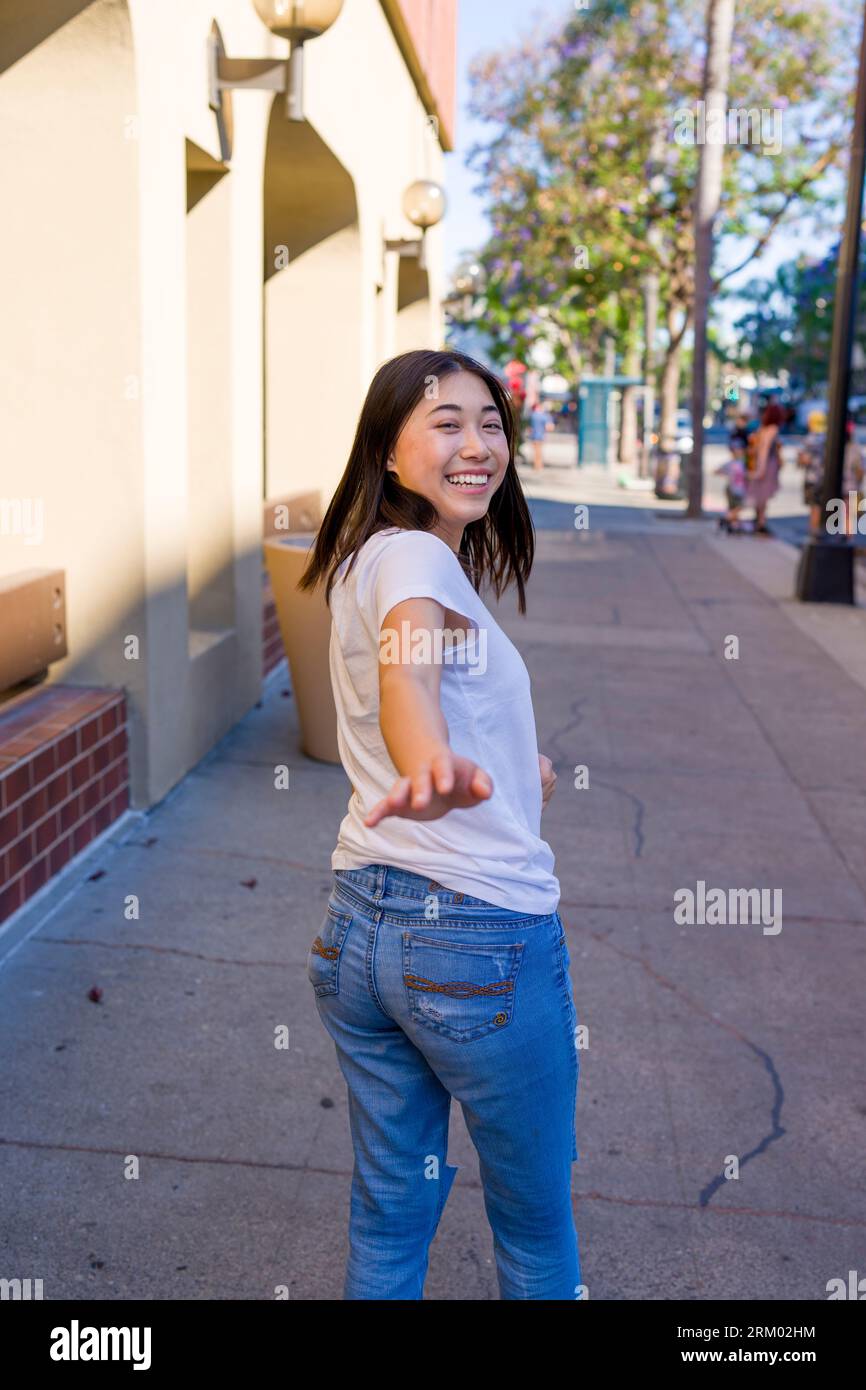 Young Asian Woman Looking Back and Reaching Hand Out to Hold | Downtown ...