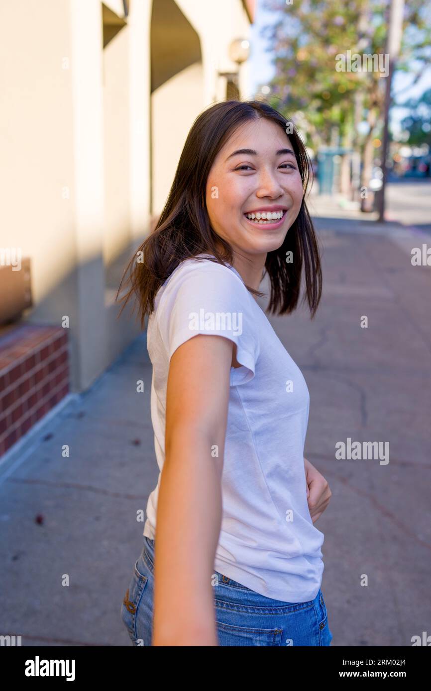Young Asian Woman Looking Back and Reaching Hand Out to Hold | Downtown ...