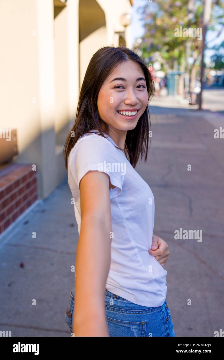 Young Asian Woman Looking Back and Reaching Hand Out to Hold | Downtown ...
