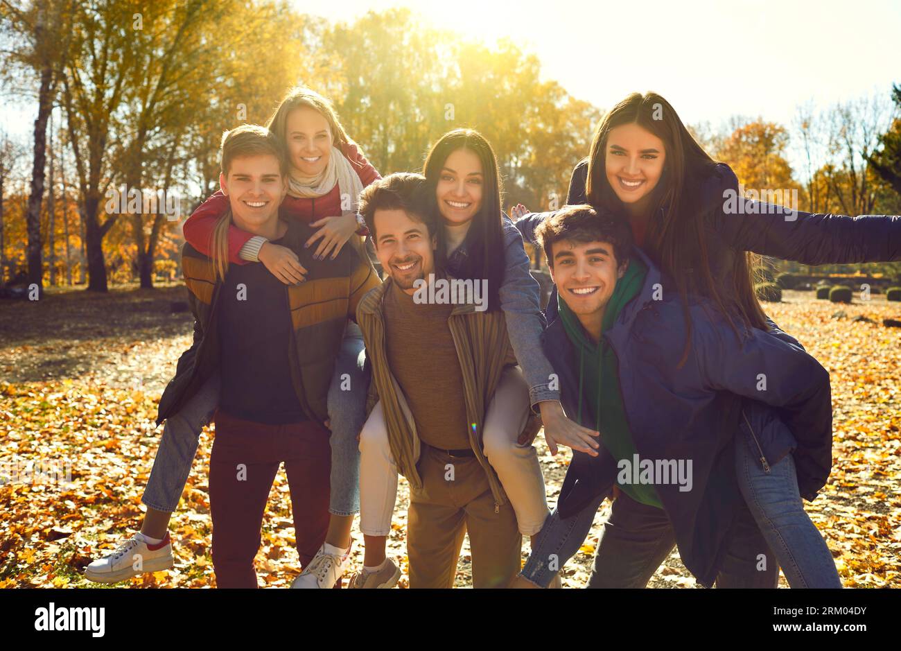 Happy young men giving piggyback ride to their female friends Stock ...