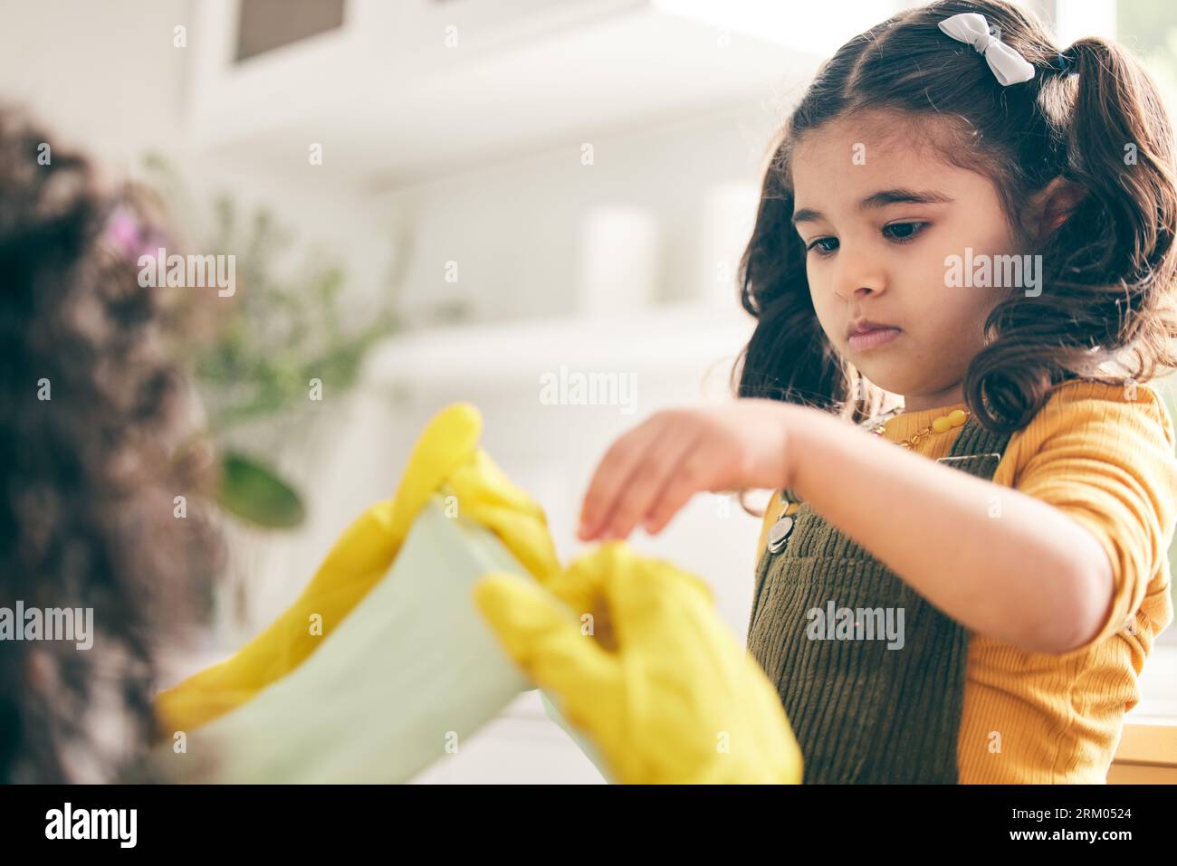 Girl, mom and kitchen to put rubber gloves on hands, helping and show ...