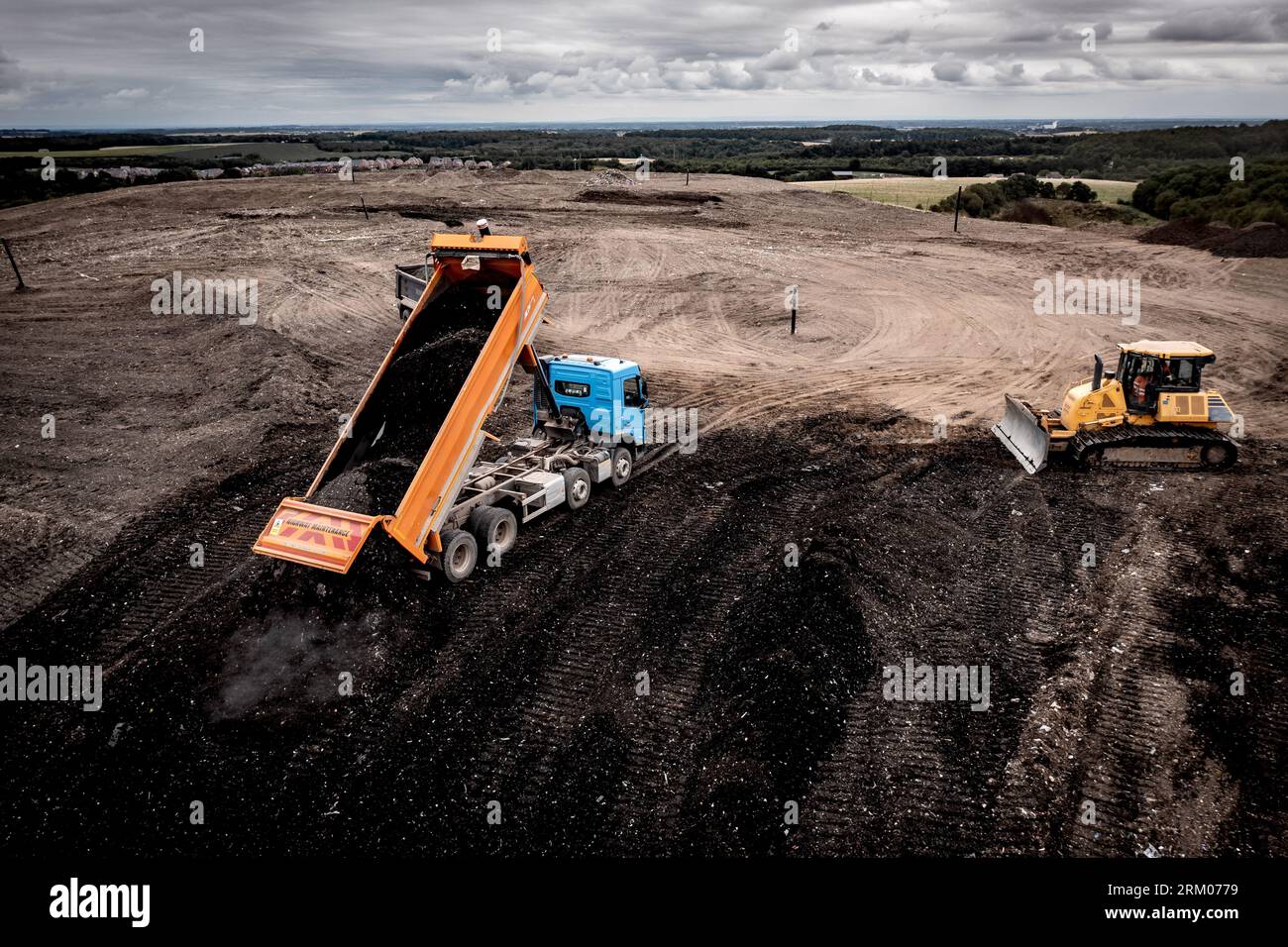 A dumper truck unloading waste at a large waste dump with tailgate ...