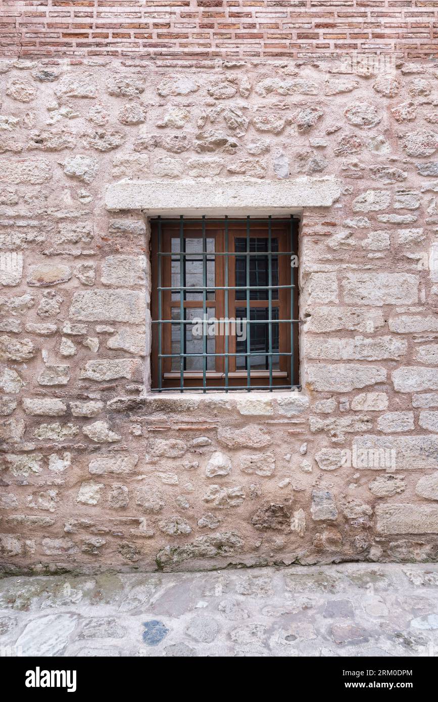 Close-up of a window with wrought iron bars in a weathered stone bricks ...