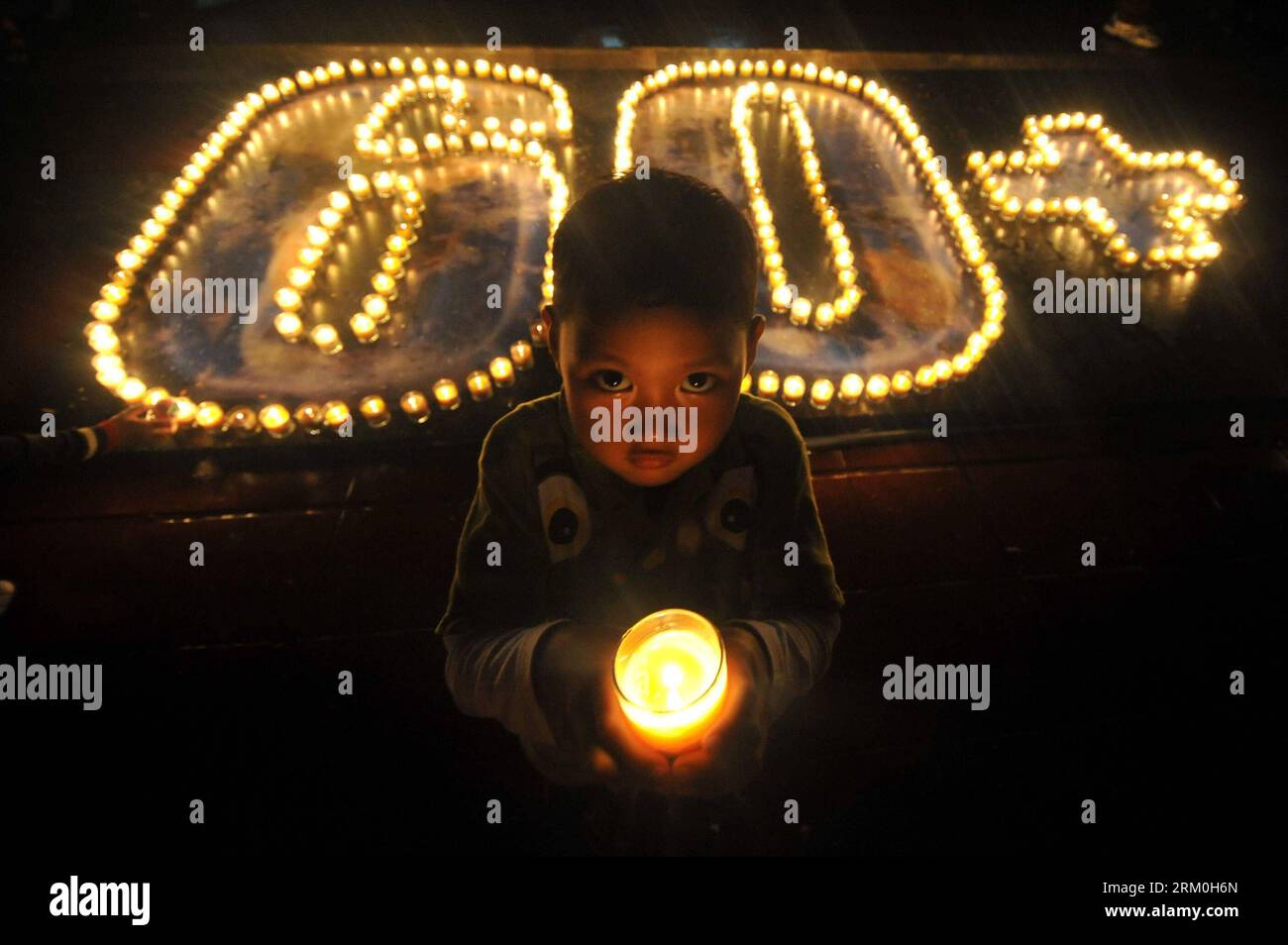 A boy holds a candle to mark the annual Earth Hour event in Jakarta ...